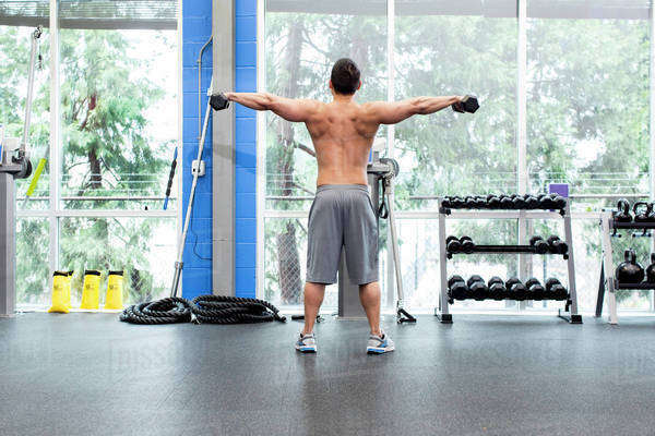 Pacific Islander man lifting weights in gym - Stock Photo - Dissolve