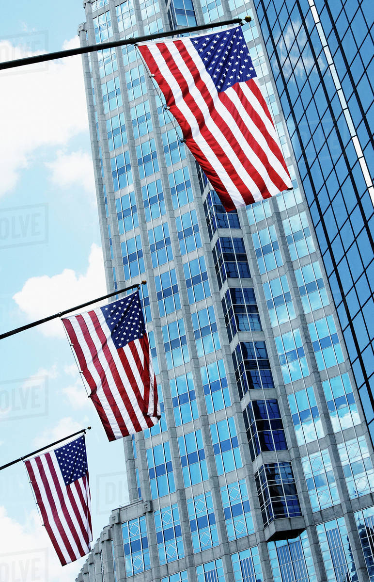 American Flags Against Office Buildings - Stock Photo - Dissolve