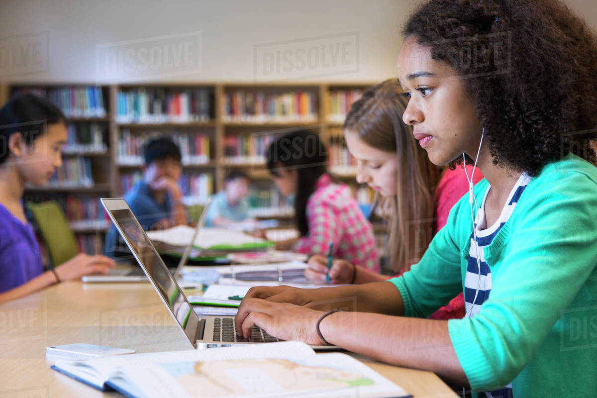 Student using laptop in library - Stock Photo - Dissolve