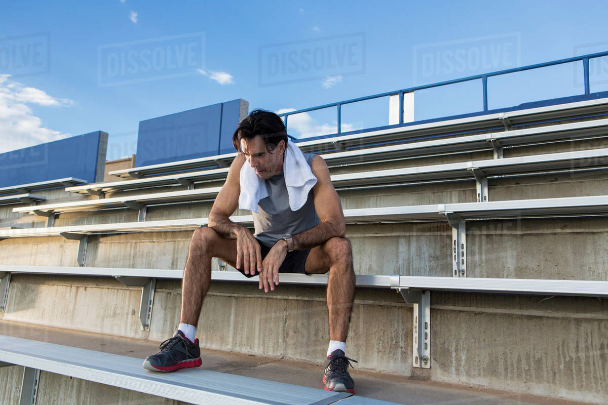 Hispanic athlete resting on bleachers - Royalty-free Stock Photo | Dissolve