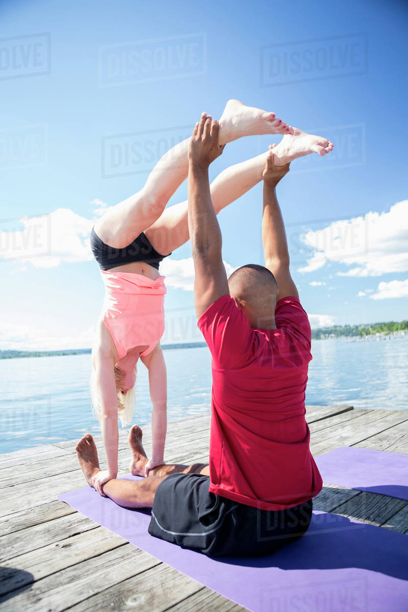 Caucasian couple practicing acroyoga on wooden dock - Royalty-free ...