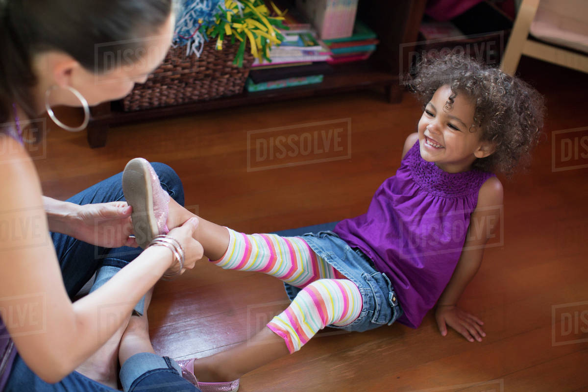 Mother putting shoes on daughter - Royalty-free Stock Photo | Dissolve