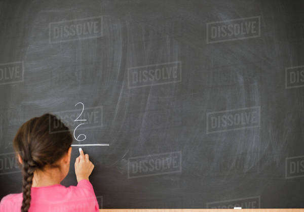 Mixed race girl doing math on blackboard - Stock Photo - Dissolve