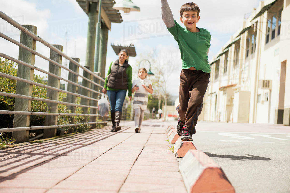 Boy balancing on edge of sidewalk - Stock Photo - Dissolve