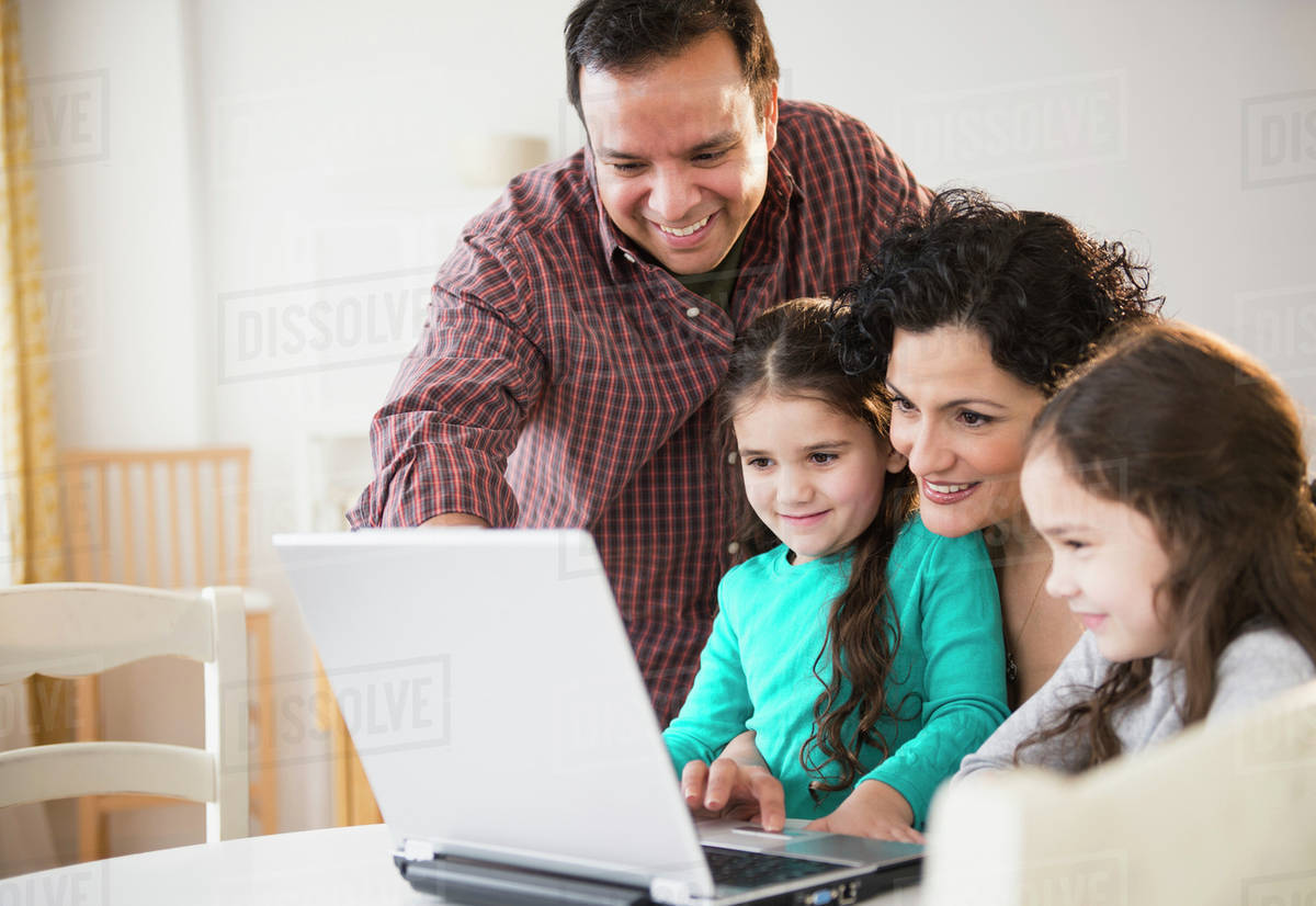 Family using laptop together at table - Royalty-free Stock Photo | Dissolve
