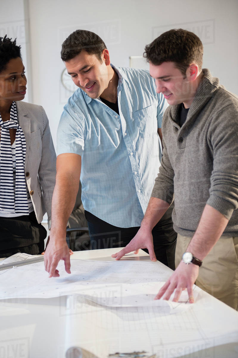 Business people examining blueprints in office - Stock Photo - Dissolve