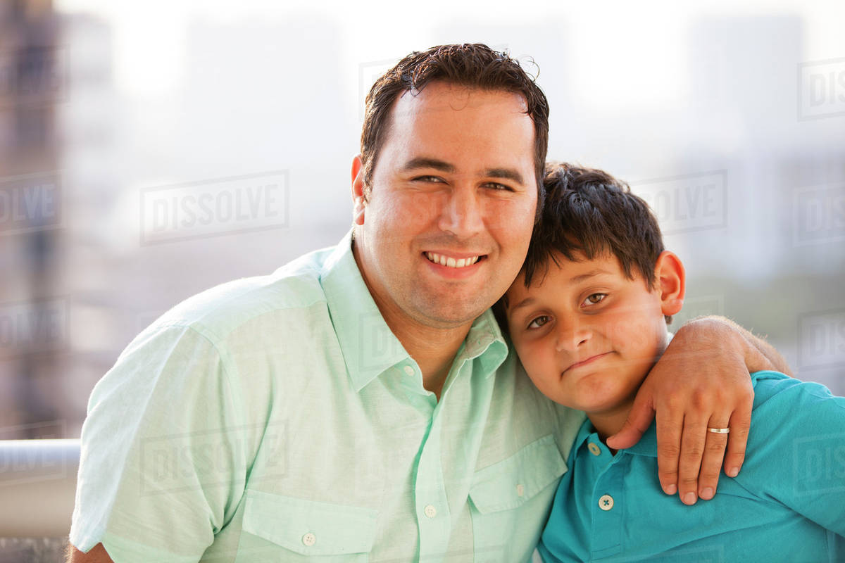 Hispanic father hugging son and smiling - Stock Photo - Dissolve