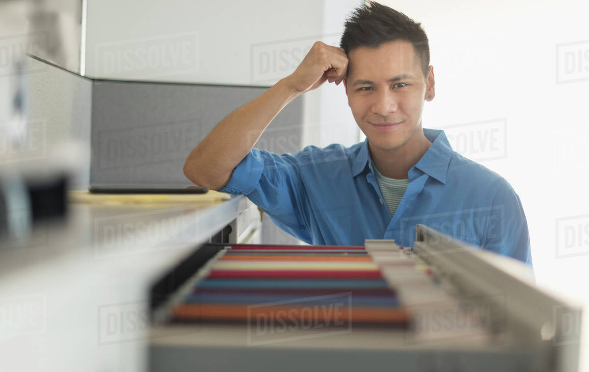 Chinese businessman smiling near filing cabinet - Royalty-free Stock ...