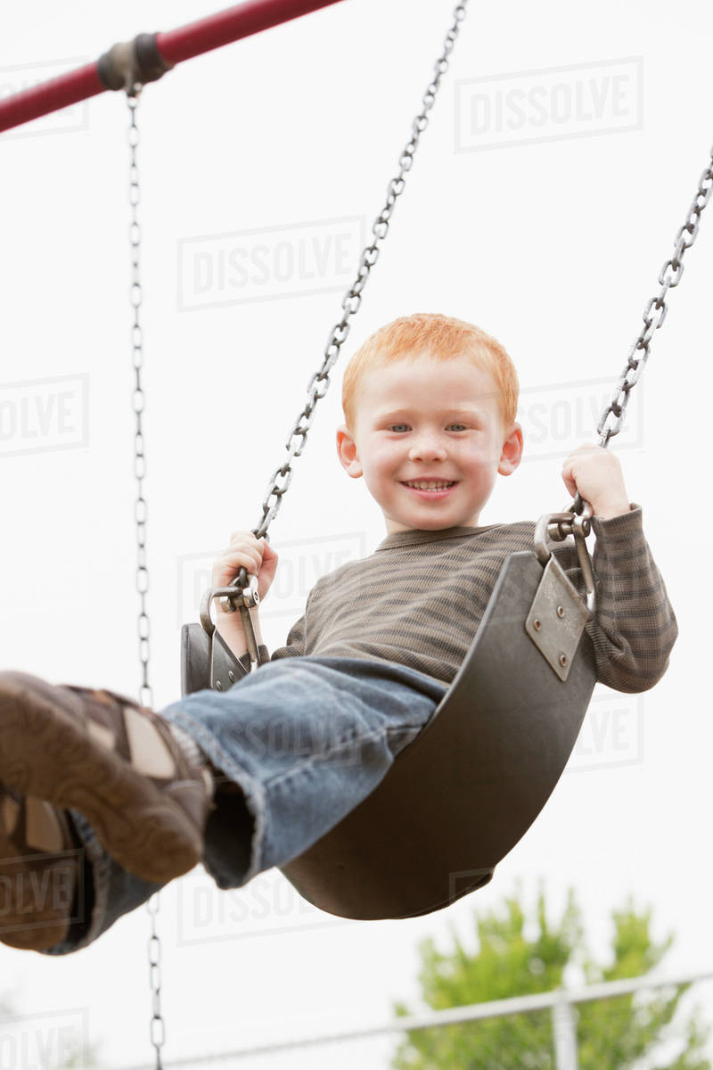 Caucasian boy sitting on playground swing - Royalty-free Stock Photo ...