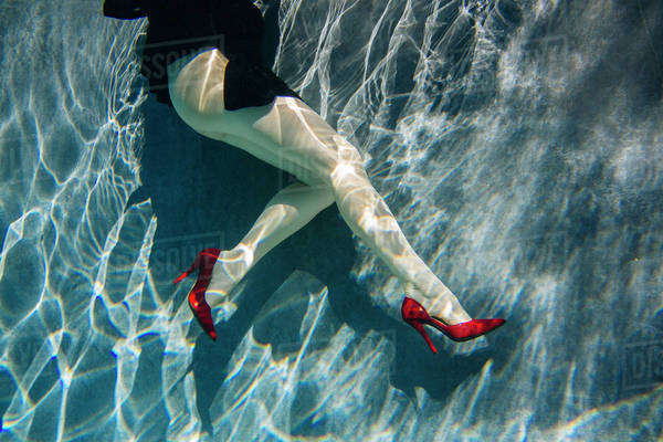 Legs of woman wearing high heels in swimming pool - Stock Photo - Dissolve