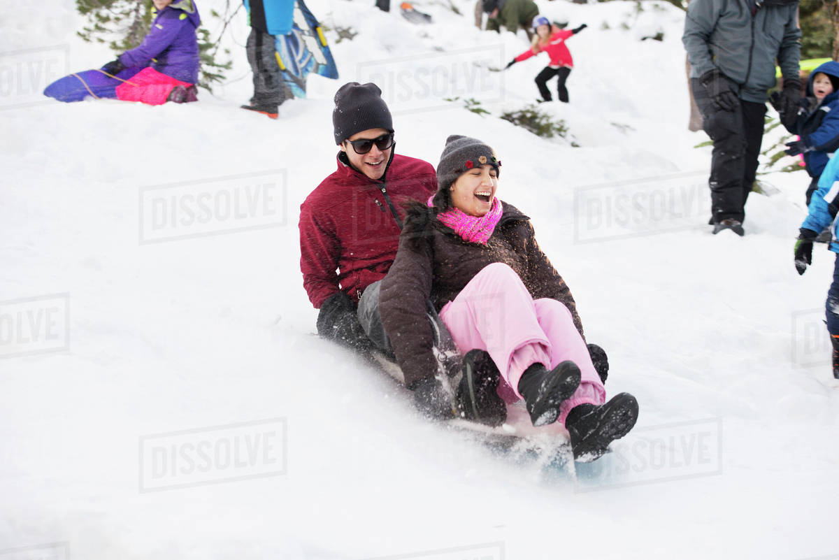 Hispanic couple sledding on snowy hillside - Royalty-free Stock Photo ...