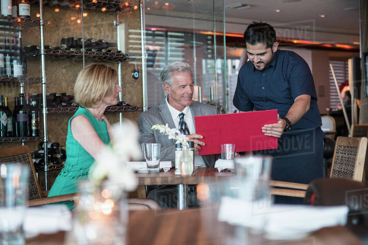 Waiter assisting couple with menu in restaurant - Royalty-free Stock ...