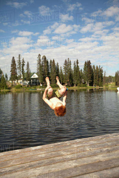 Caucasian boy jumping into lake - Royalty-free Stock Photo | Dissolve