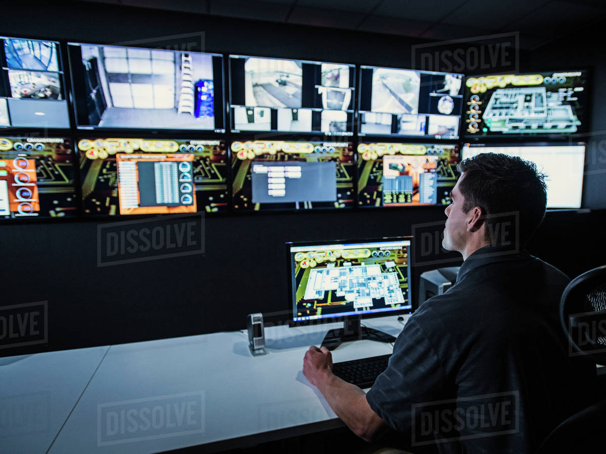 Hispanic security guard watching monitors in control room - Stock Photo ...