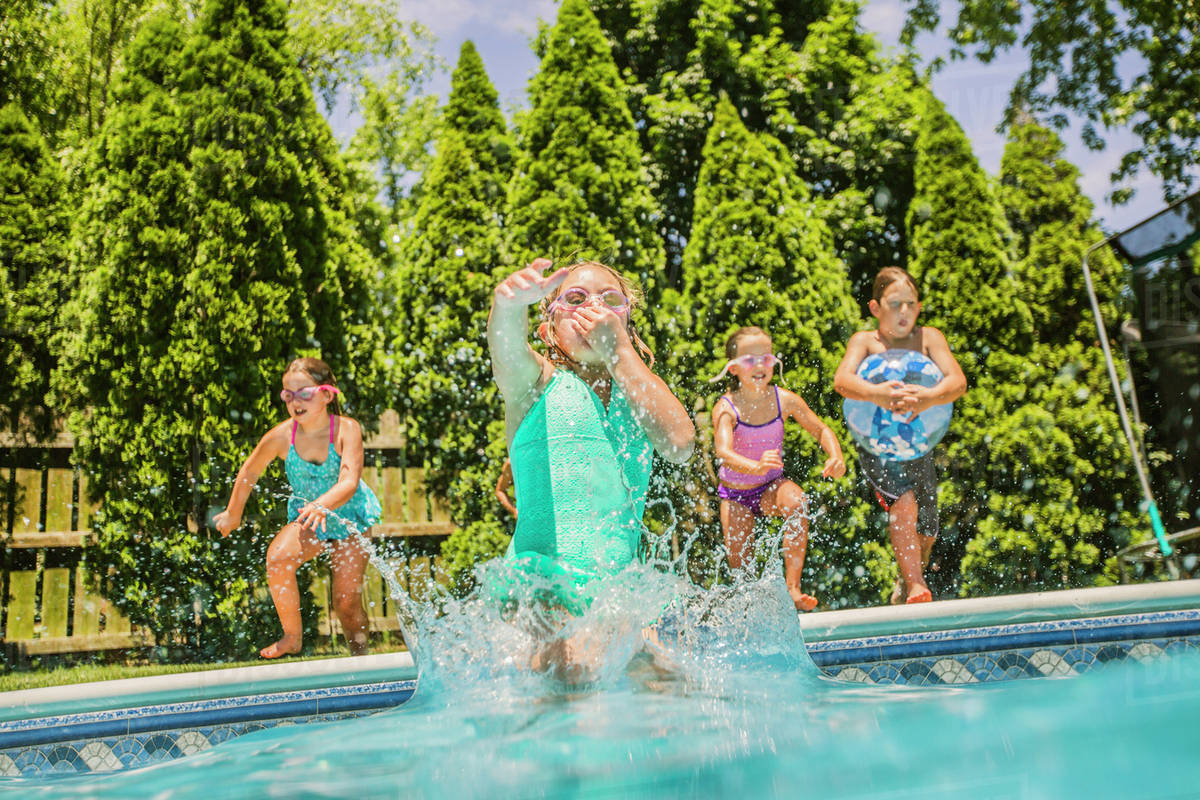 Caucasian girls jumping into swimming pool - Stock Photo - Dissolve