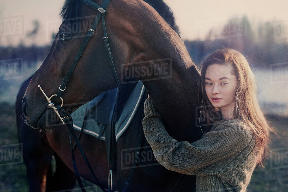 Caucasian woman hugging horse in field - Stock Photo - Dissolve