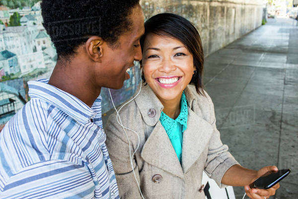 Couple listening to cell phone on city sidewalk - Royalty-free Stock ...