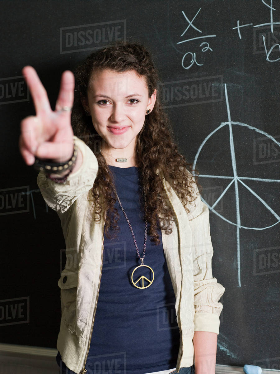 Student giving peace sign at chalkboard in classroom - Stock Photo ...