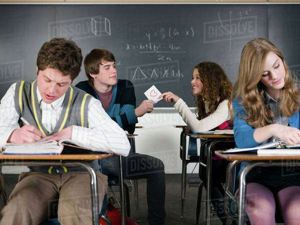 Students passing love note in classroom - Stock Photo - Dissolve
