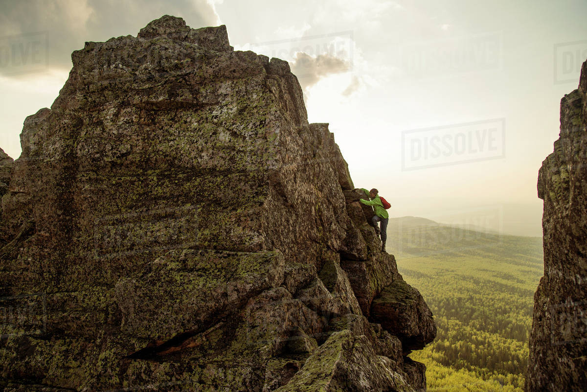 Caucasian hiker climbing on rock formation - Stock Photo - Dissolve