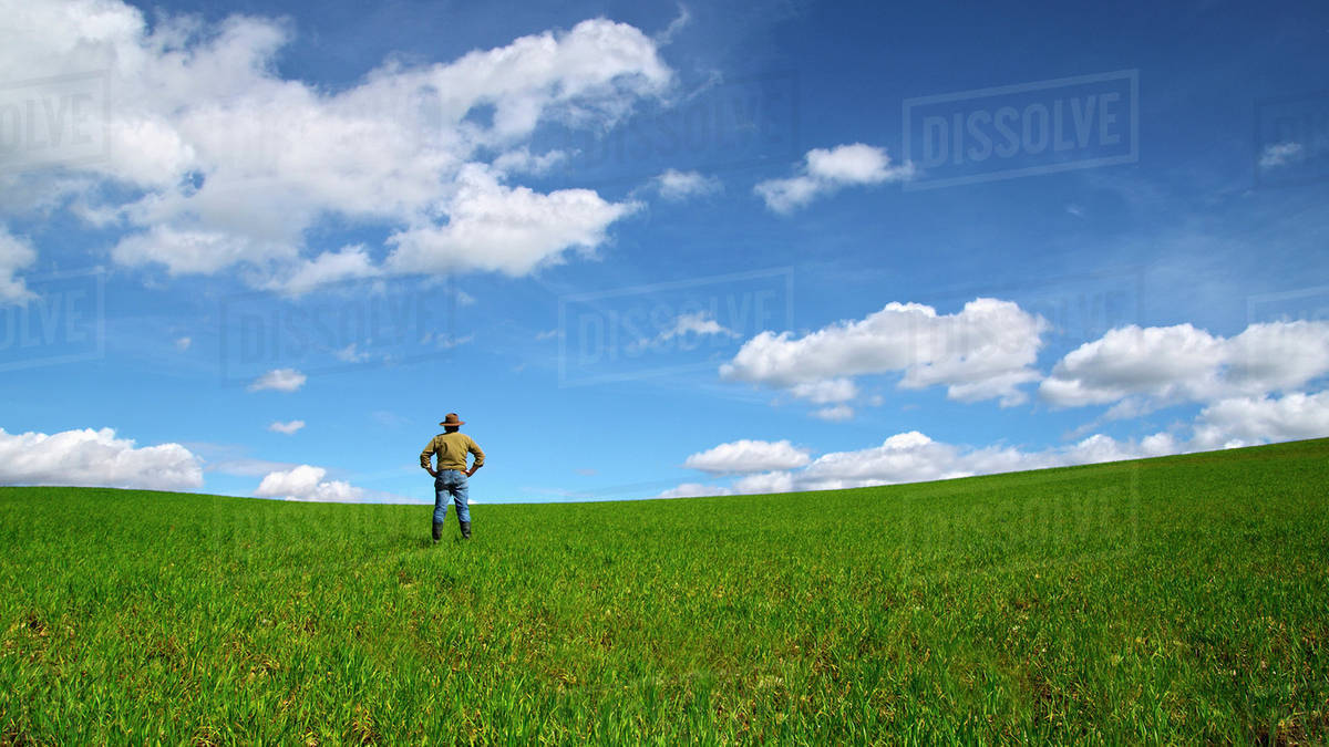 Caucasian man standing in rural field - Royalty-free Stock Photo | Dissolve