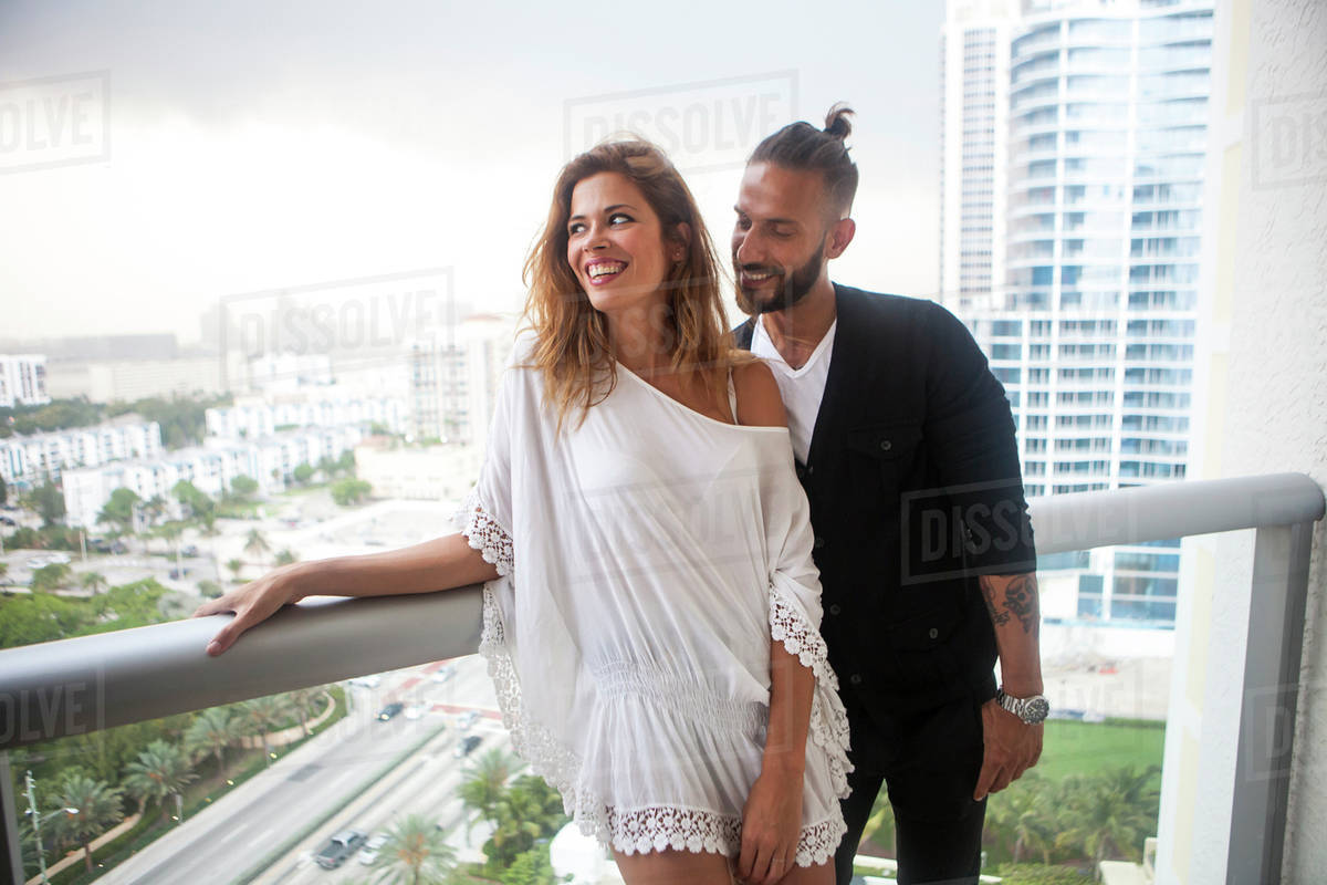 Hispanic couple standing on urban balcony - Stock Photo - Dissolve