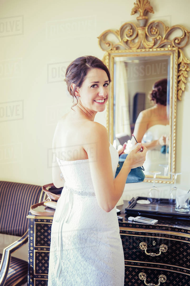 Caucasian bride applying makeup in mirror - Stock Photo - Dissolve