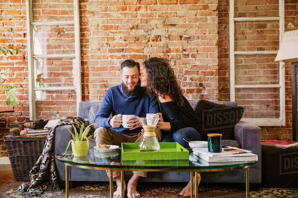 Couple drinking coffee on sofa in living room - Royalty-free Stock ...