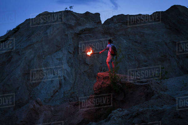 Caucasian man holding torch under rocky cliff - Royalty-free Stock ...