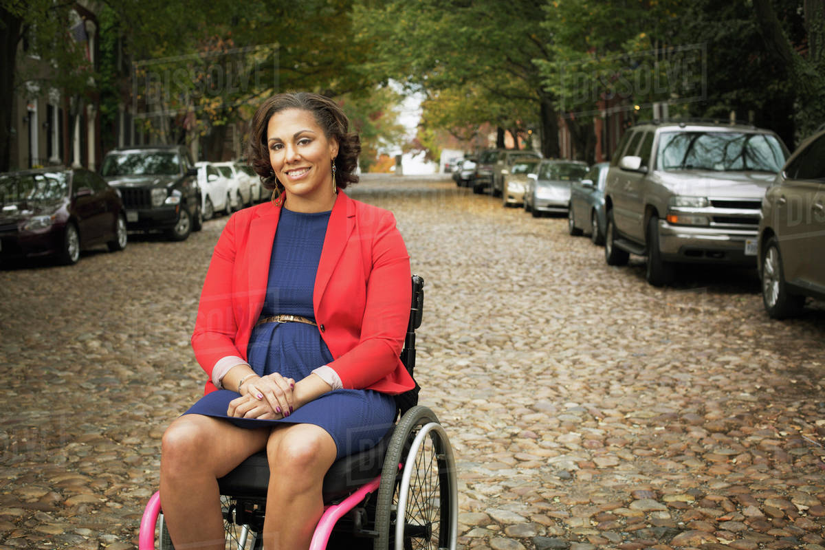 Disabled woman smiling in wheelchair on cobblestone street - Stock ...