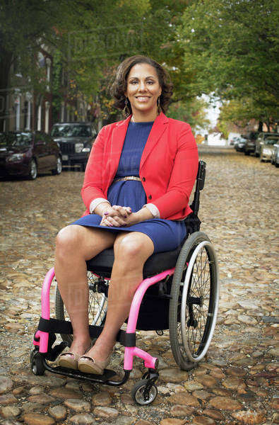 Disabled woman smiling in wheelchair on cobblestone street - Royalty ...