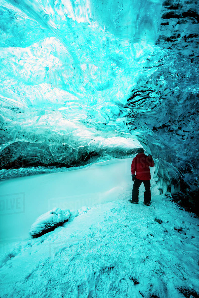 Hiker walking in ice cave - Royalty-free Stock Photo | Dissolve