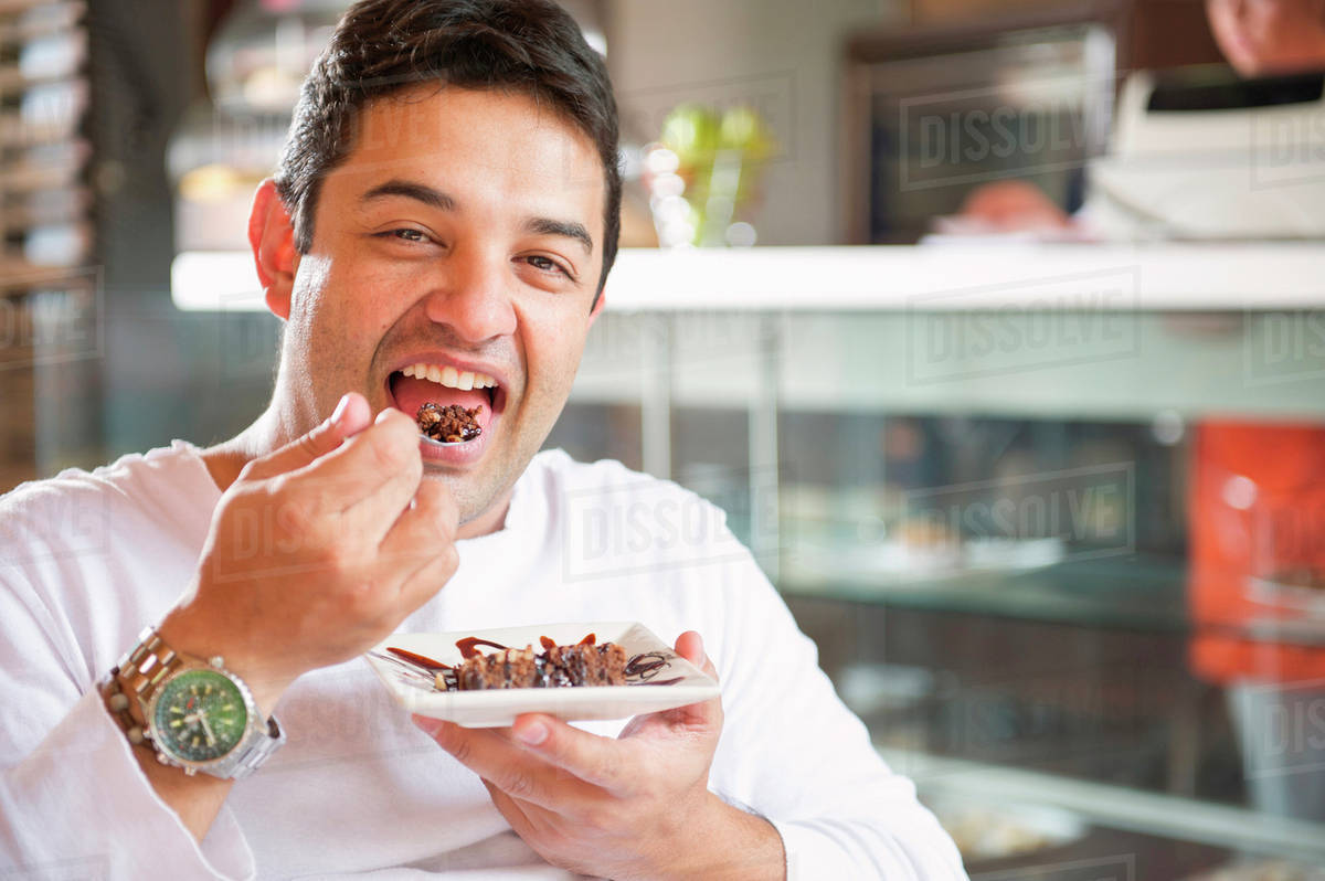 Hispanic man eating dessert in cafe - Stock Photo - Dissolve