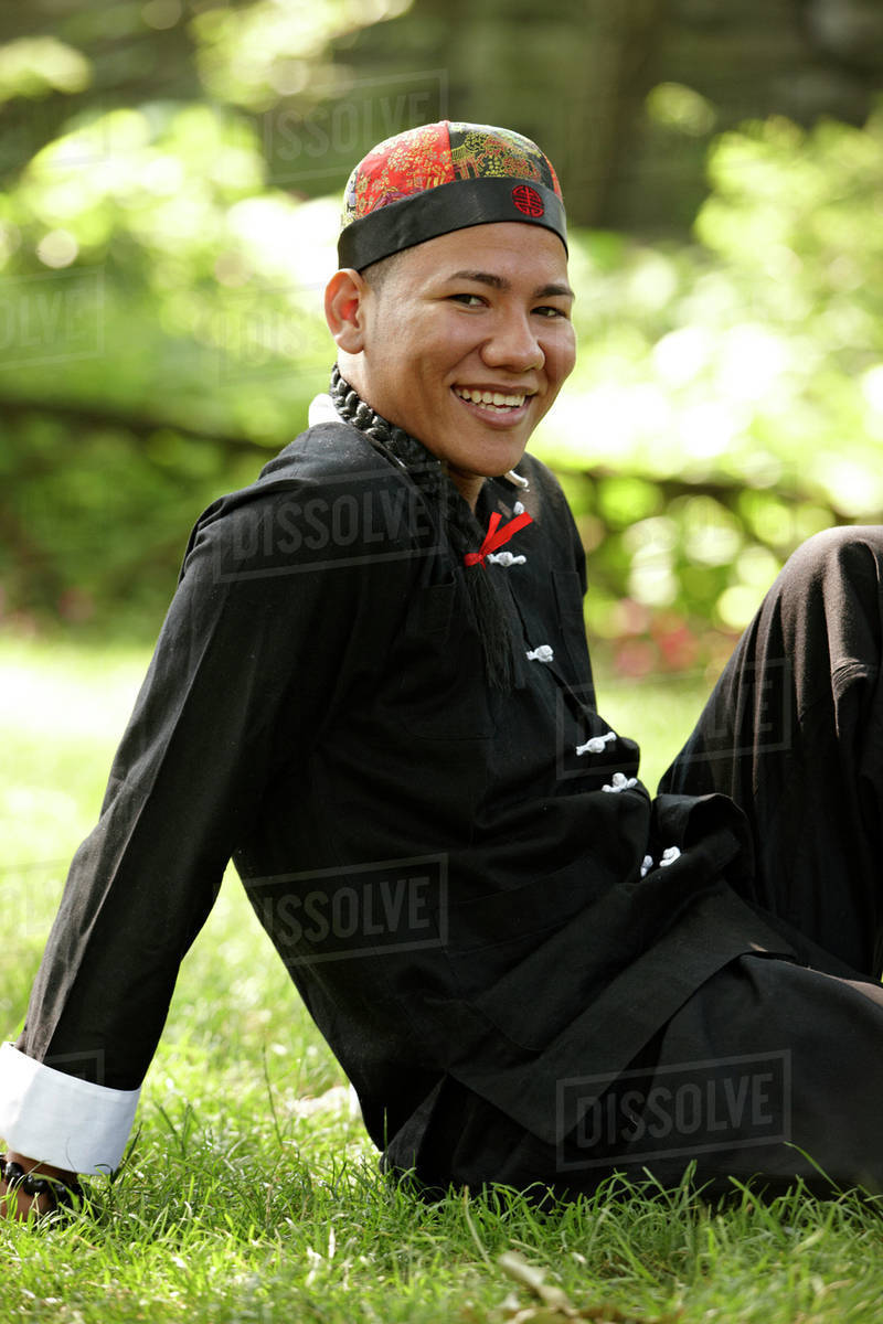 Man in traditional Asian clothing sitting in grass - Royalty-free Stock ...