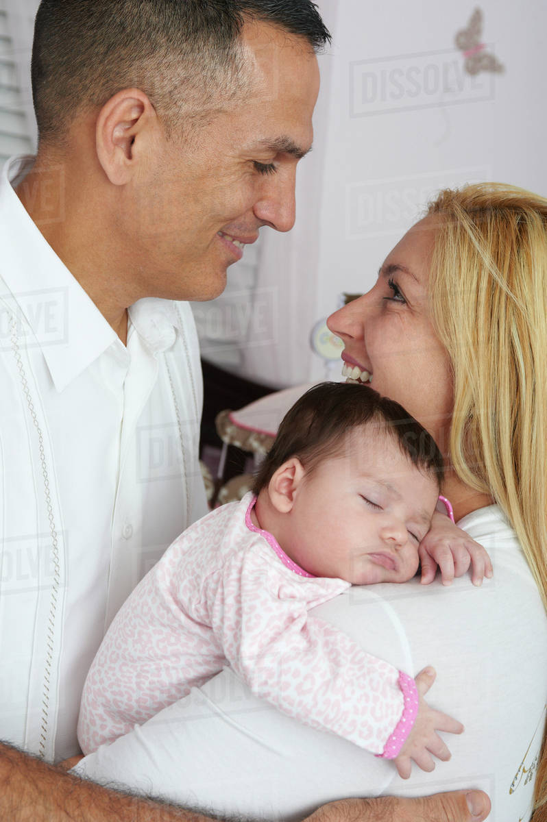 Hispanic parents holding baby daughter - Stock Photo - Dissolve
