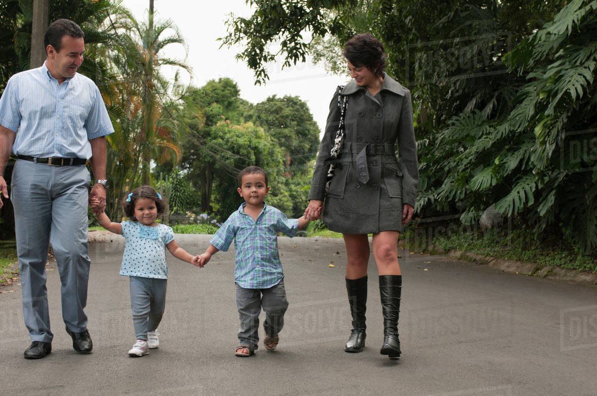 Hispanic parents holding children's hands outdoors - Stock Photo - Dissolve