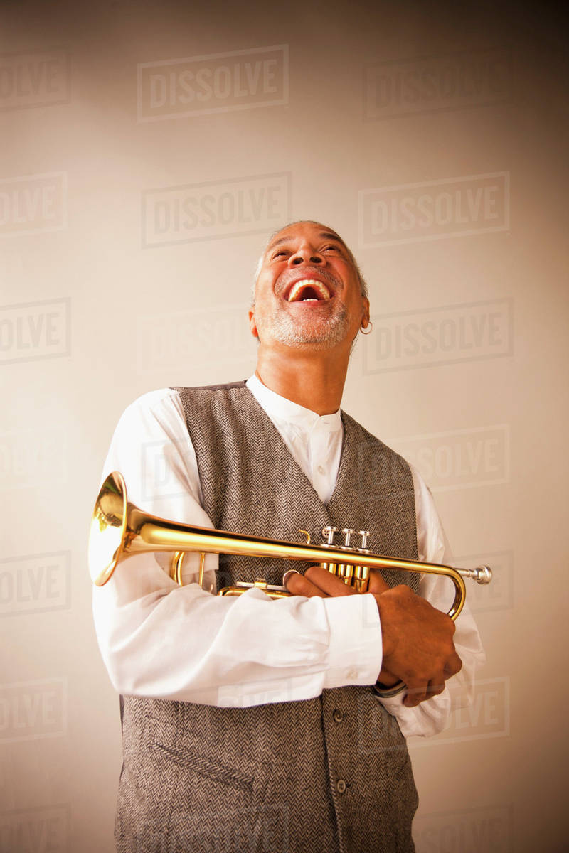 Laughing musician holding trumpet - Stock Photo - Dissolve