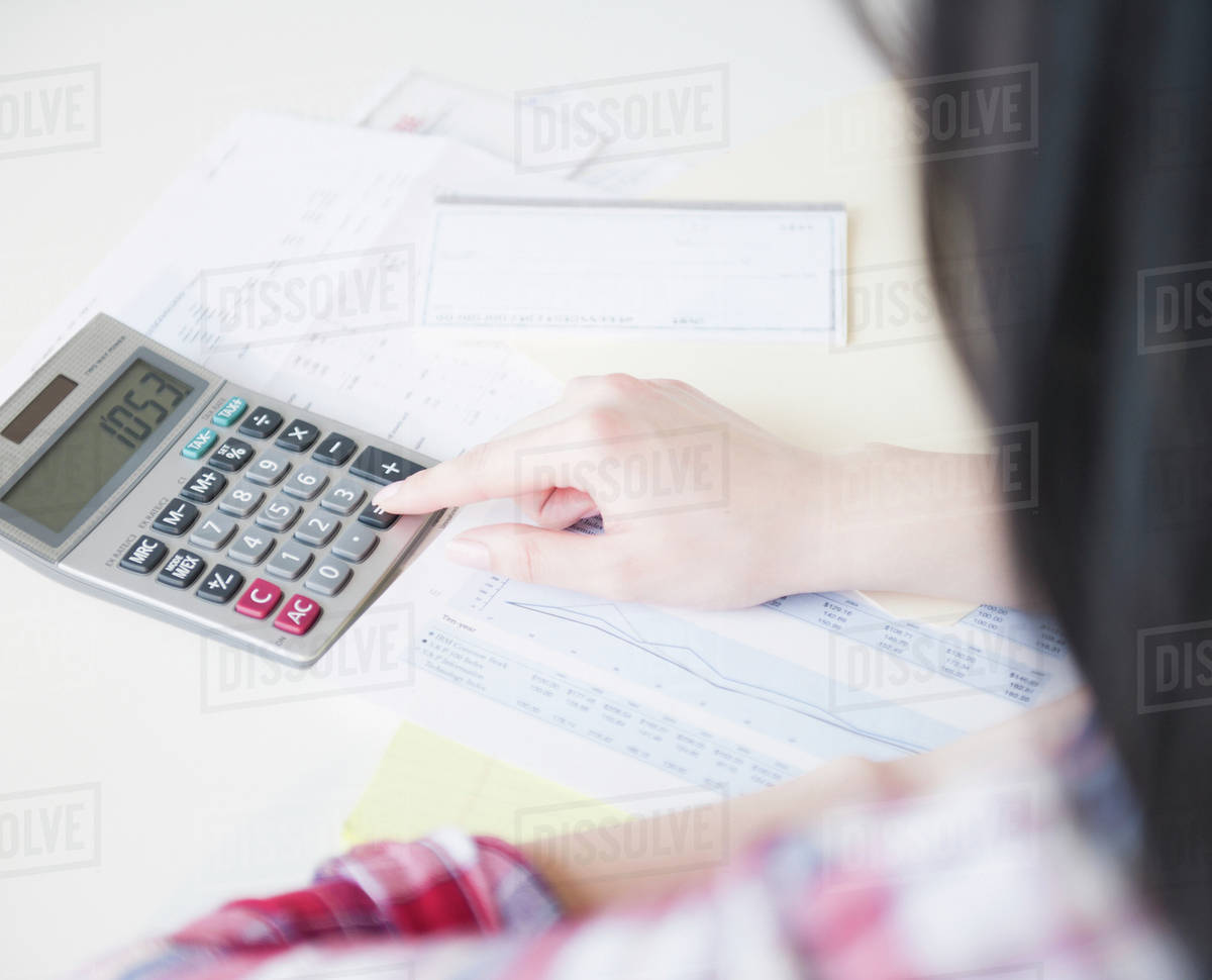 Korean woman using calculator - Stock Photo - Dissolve