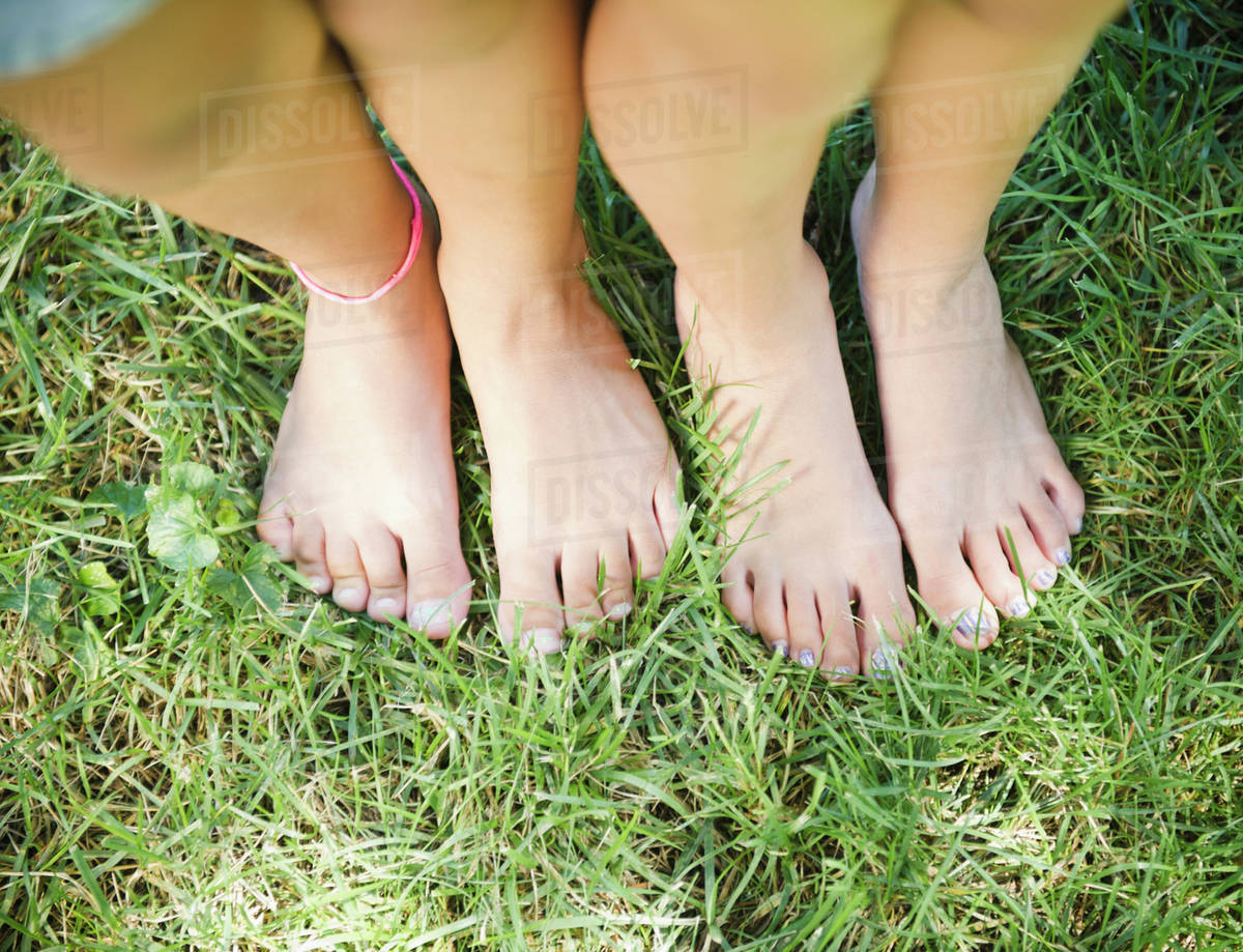 Hispanic girls feet standing in grass - Royalty-free Stock Photo | Dissolve