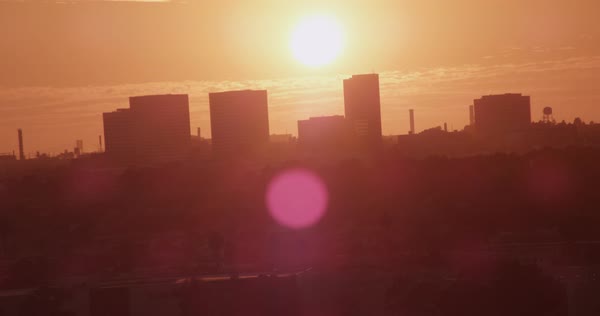 Helicopter aerial shot of yellow haze from sunset over city skyline ...