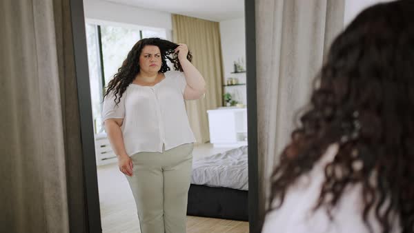 Young overweight woman looks at mirror with disappointment - 4K Royalty ...