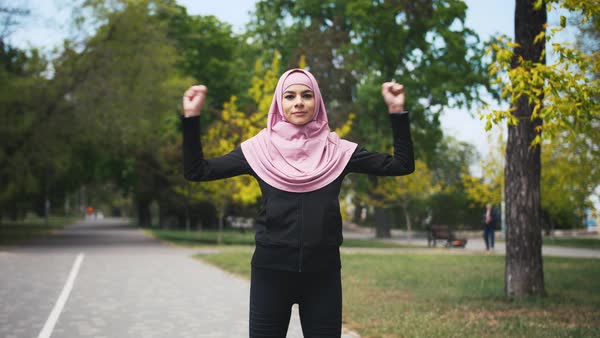 Young fitness muslim woman doing sport exercises before run in park ...