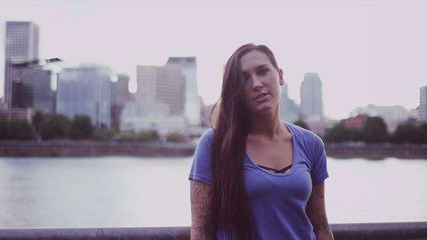 Beautiful girl standing in front of a view of downtown, slow motion ...