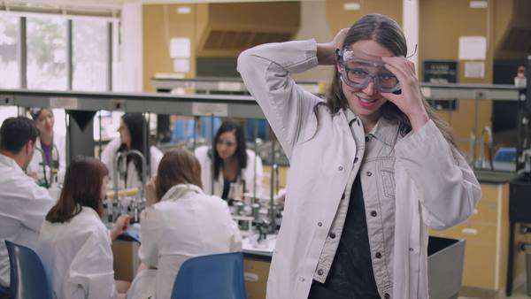 Portrait of a student in a science lab putting on safety goggles and ...