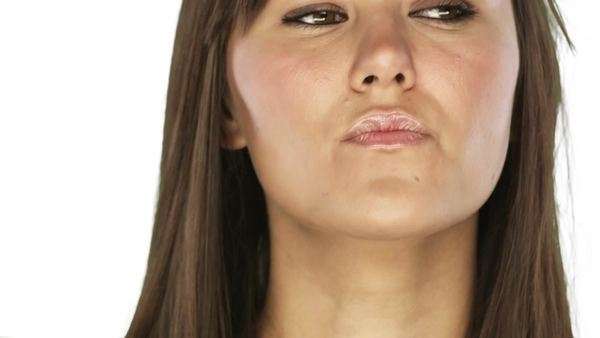 Woman looks with a upset face into the camera on a white background ...