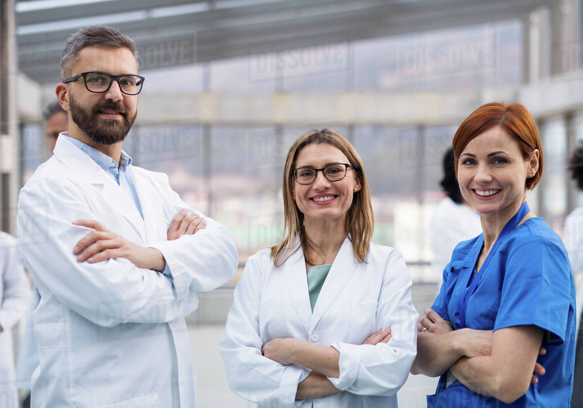 Group of doctors standing in corridor on medical conference, looking at ...
