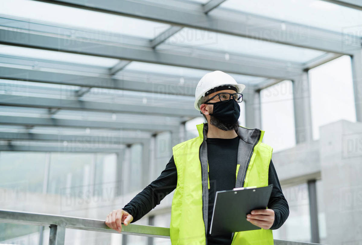Portrait of worker with face mask, helmet and high visibility vest ...