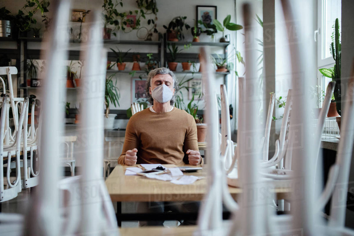 Frustrated owner sitting at table in closed cafe or coffee shop, small ...