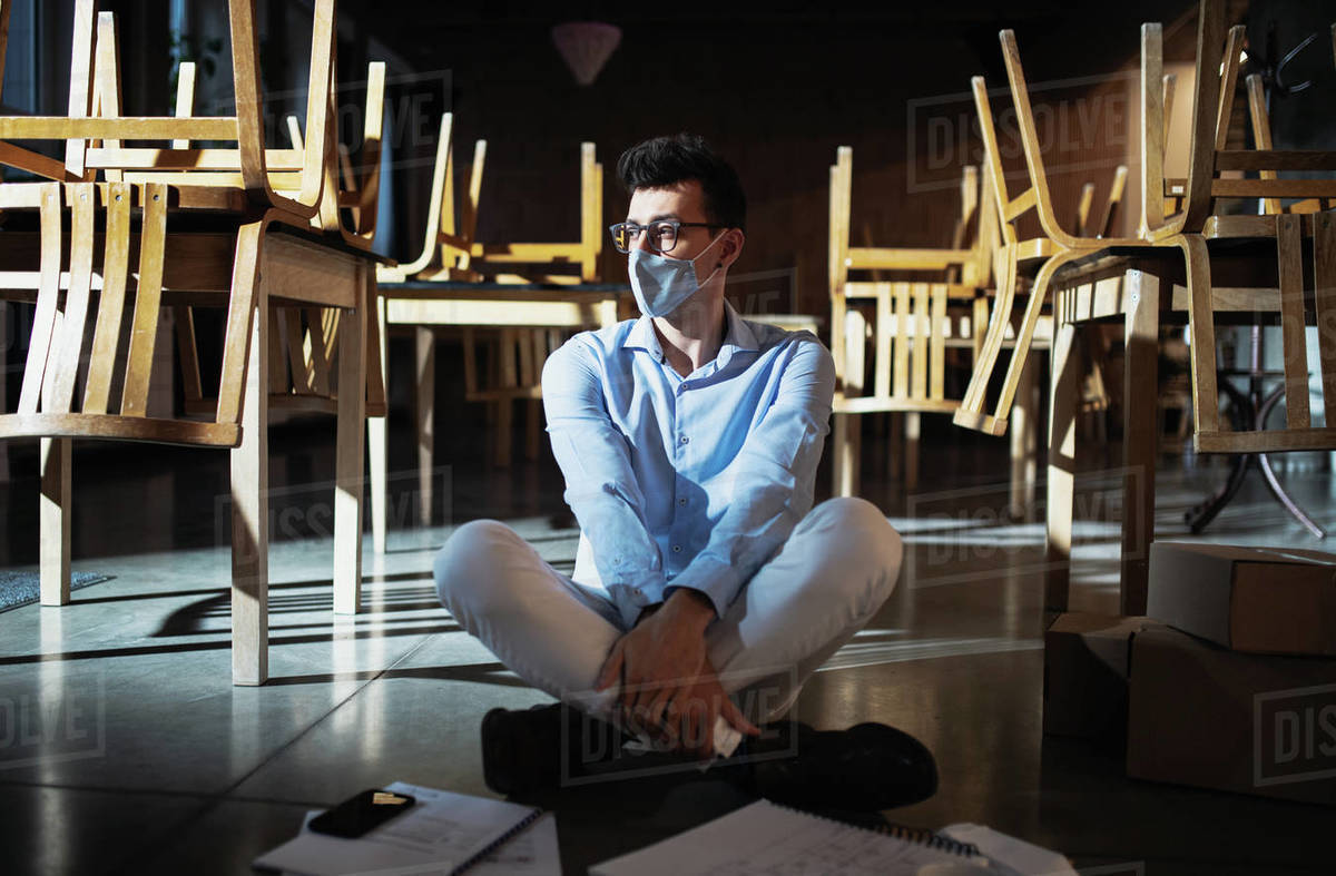 Frustrated owner sitting on floor in closed cafe or coffee shop, small ...