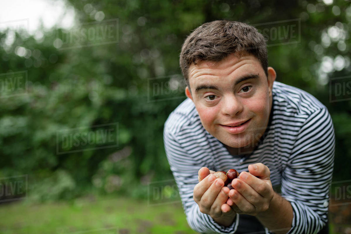 Portrait of down syndrome adult man standing outdoors at green ...